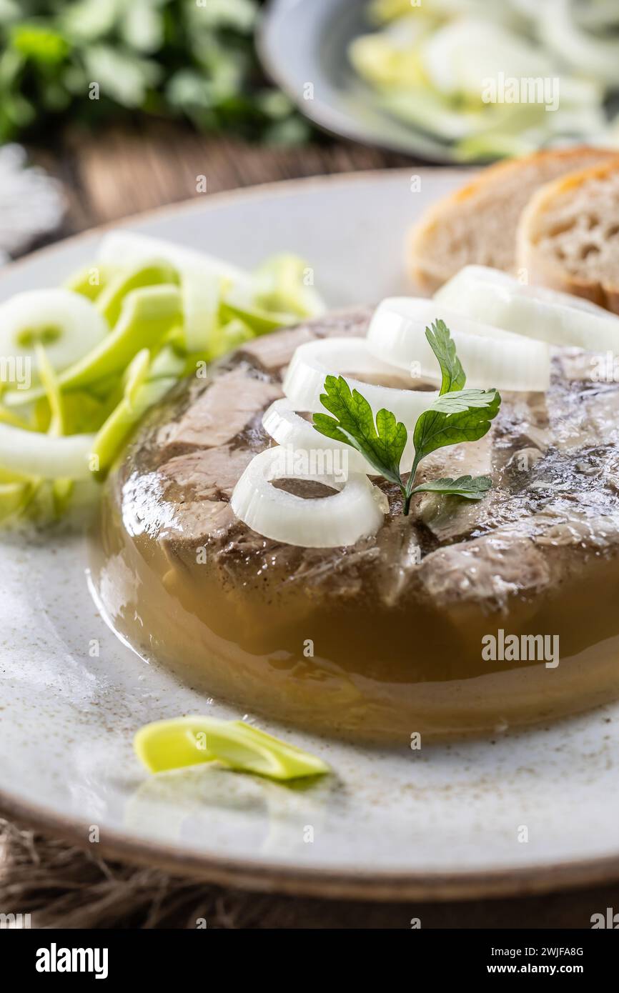 Homemade pork aspic, meat jelly with onion and leek in a white plate ...