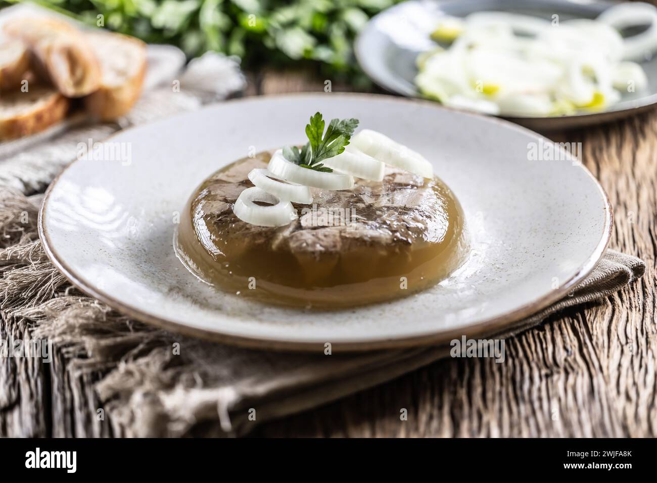 Homemade pork aspic, meat jelly with onion and leek in a white plate ...
