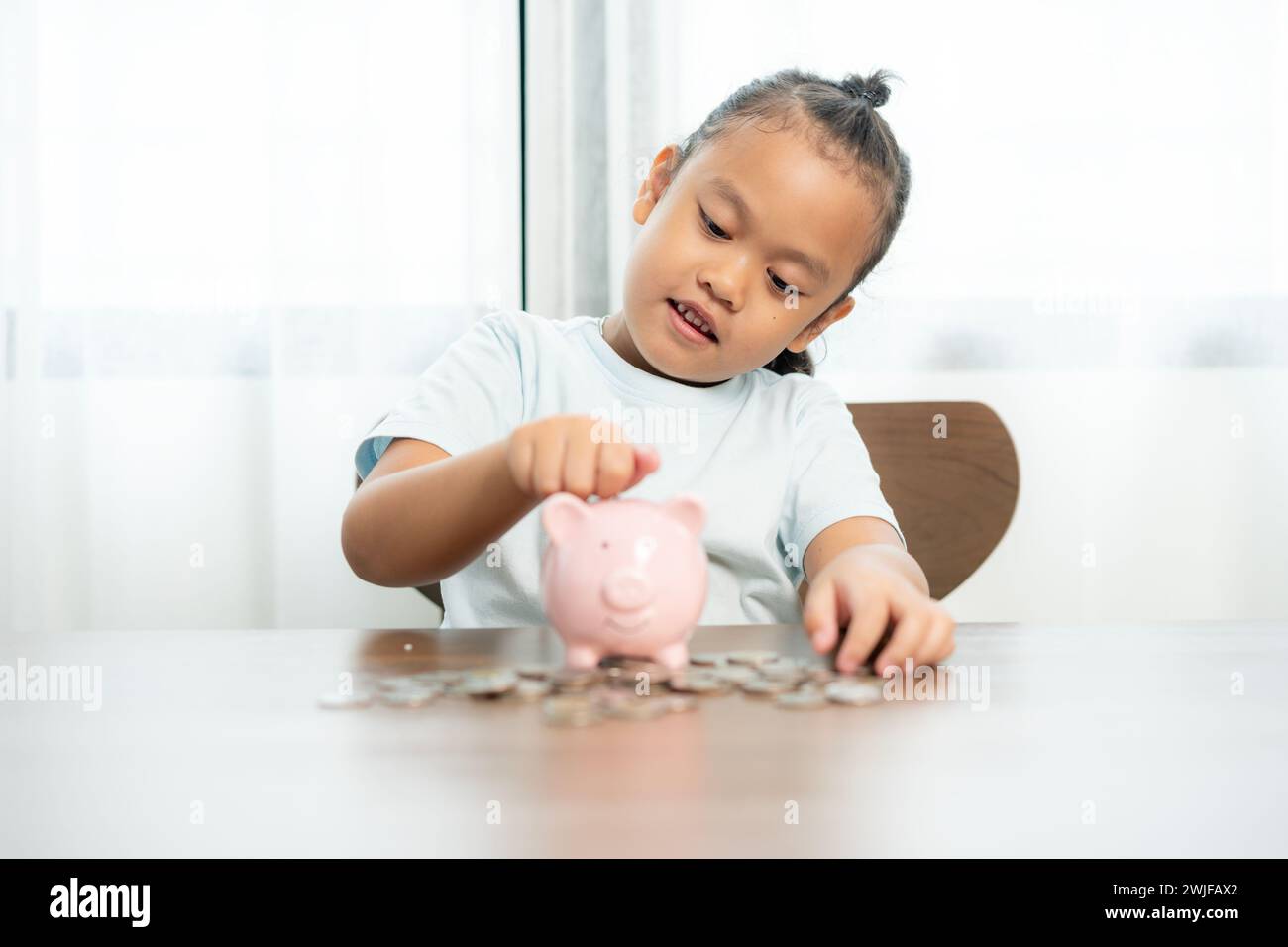 A girl saving money, putting coins into a piggy bank for the future ...