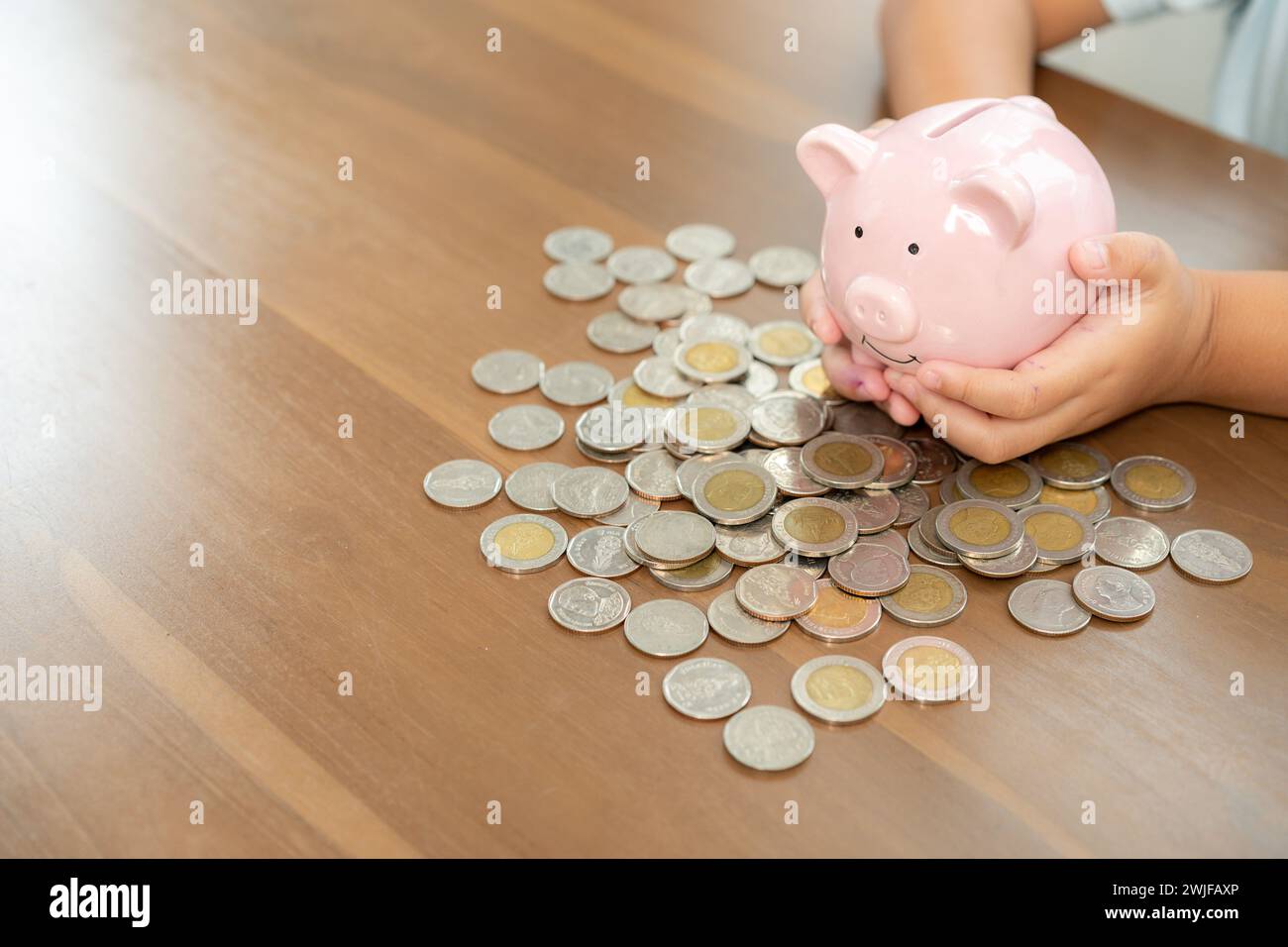 A girl saving money, putting coins into a piggy bank for the future ...