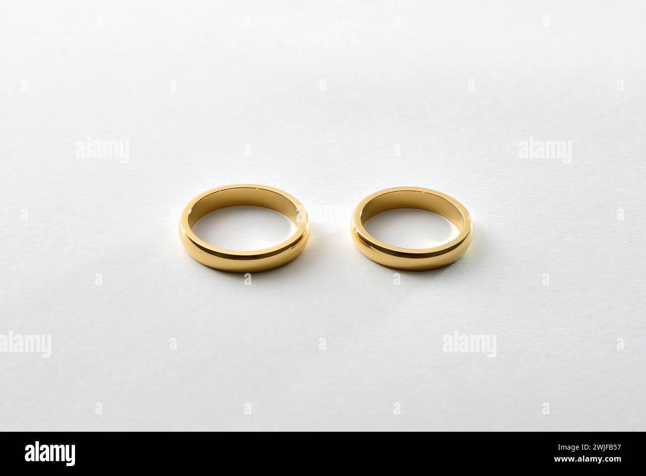 Detail of engagement gold rings side by side on white textured base ...