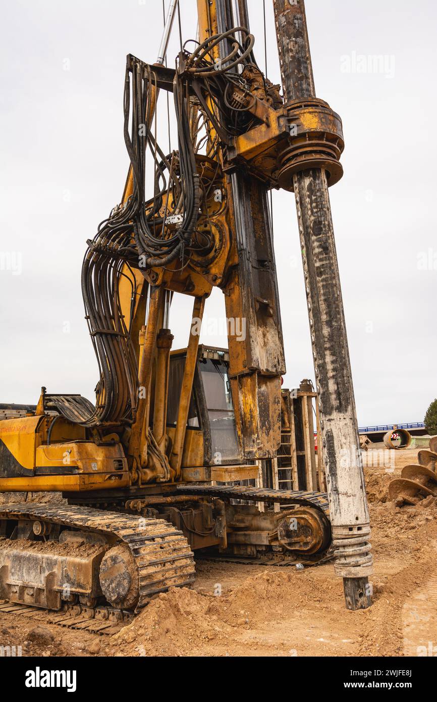 A massive yellow drilling machine operates amidst rocky terrain and ...