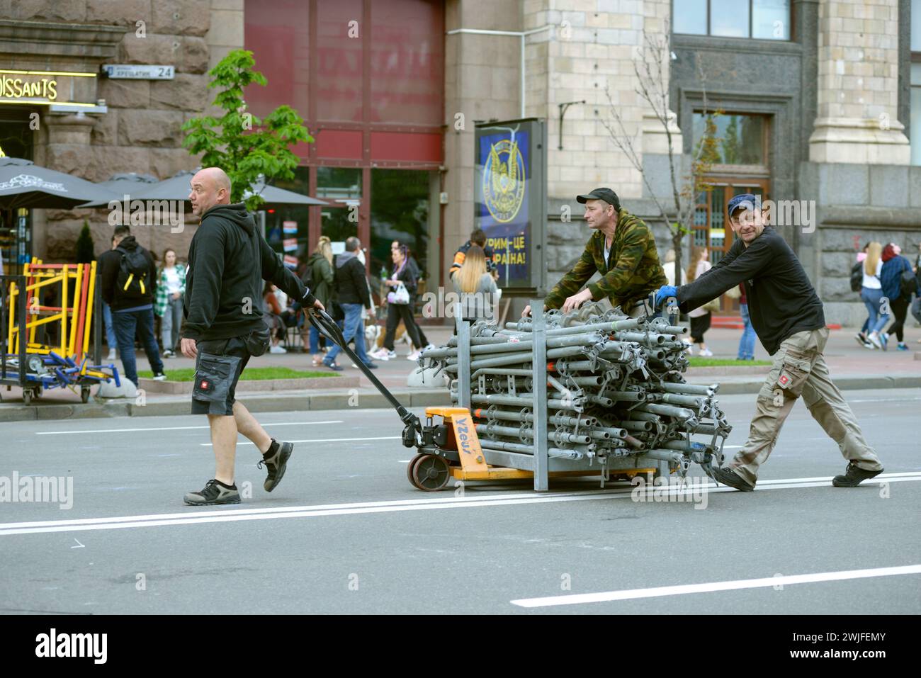 Men workers pulling the cart with balks for scaffolding in the street ...