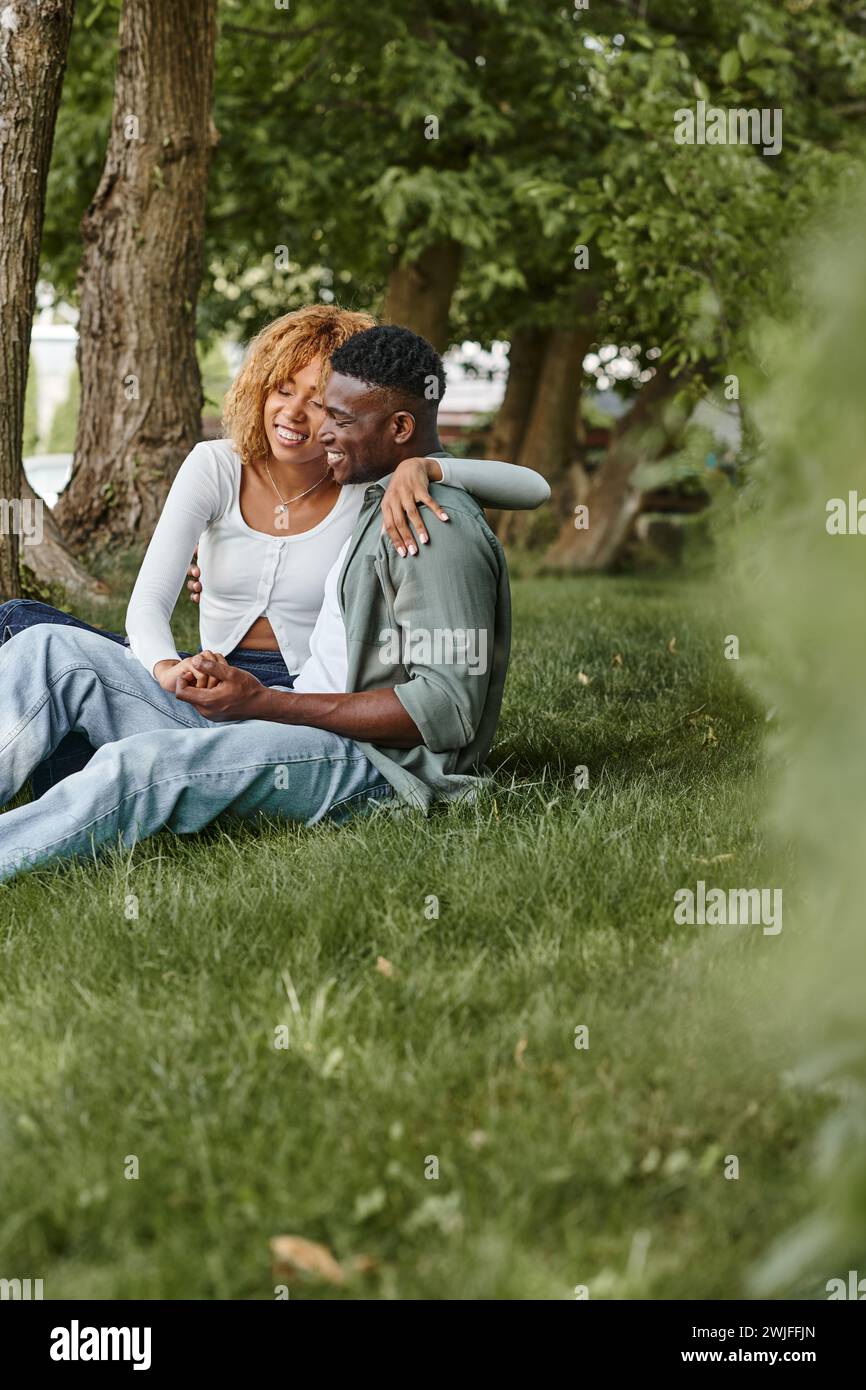 Happy African American Couple In Casual Wear Hugging While Sitting