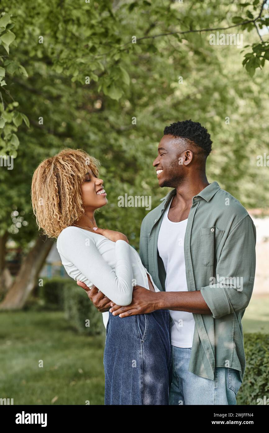 african american couple laughing and hugging each other outdoors, black ...