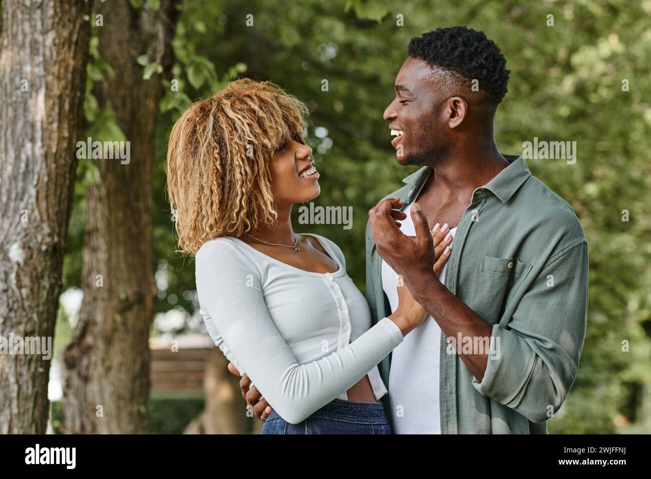 pleased african american couple hugging each other and smiling outdoors ...