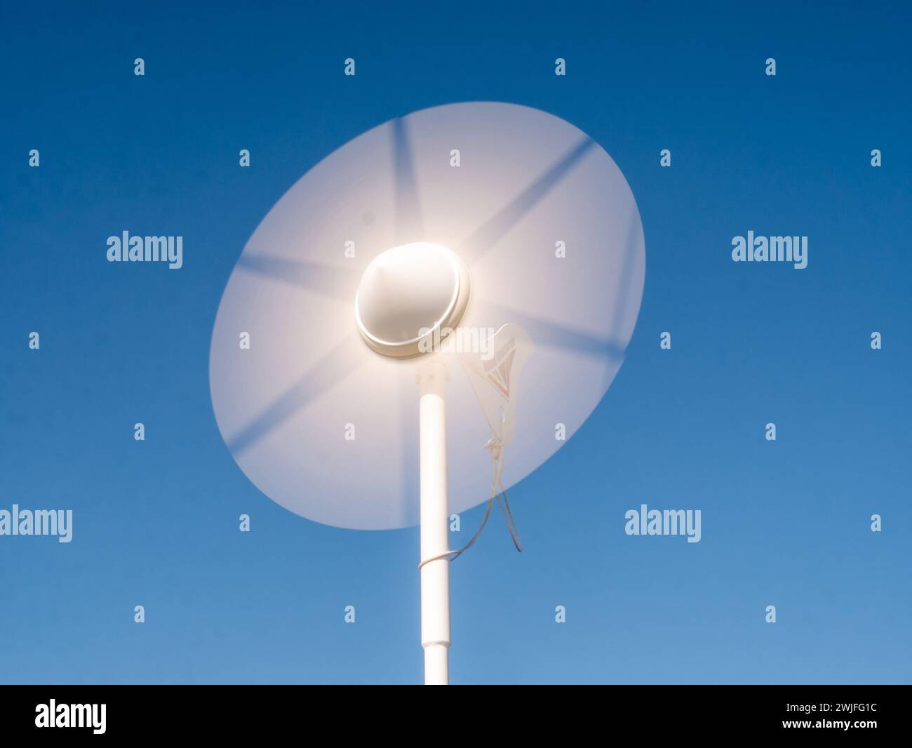 Blades of white wind charger spinning against a blue sky, sustainable ...