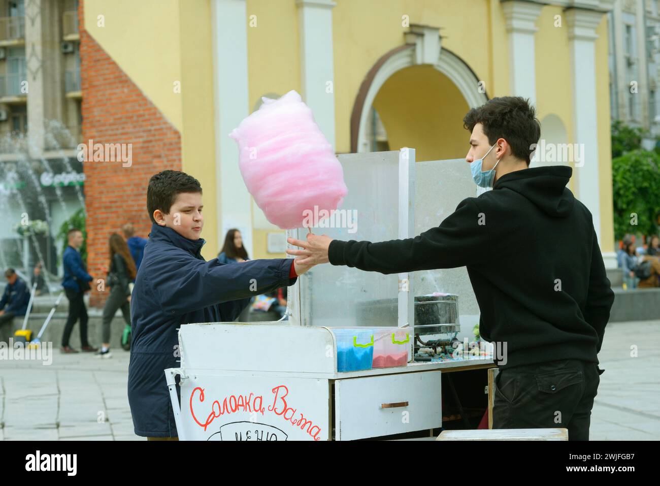 Young man street sweets seller selling cotton candy to the teen boy ...