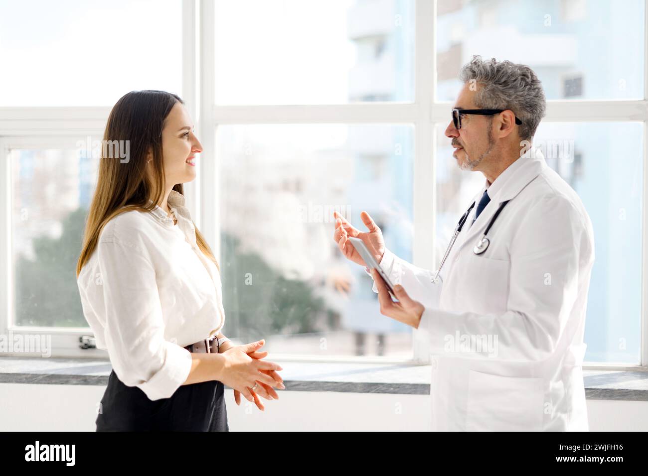 A senior doctor engaged in a conversation with a young female patient ...