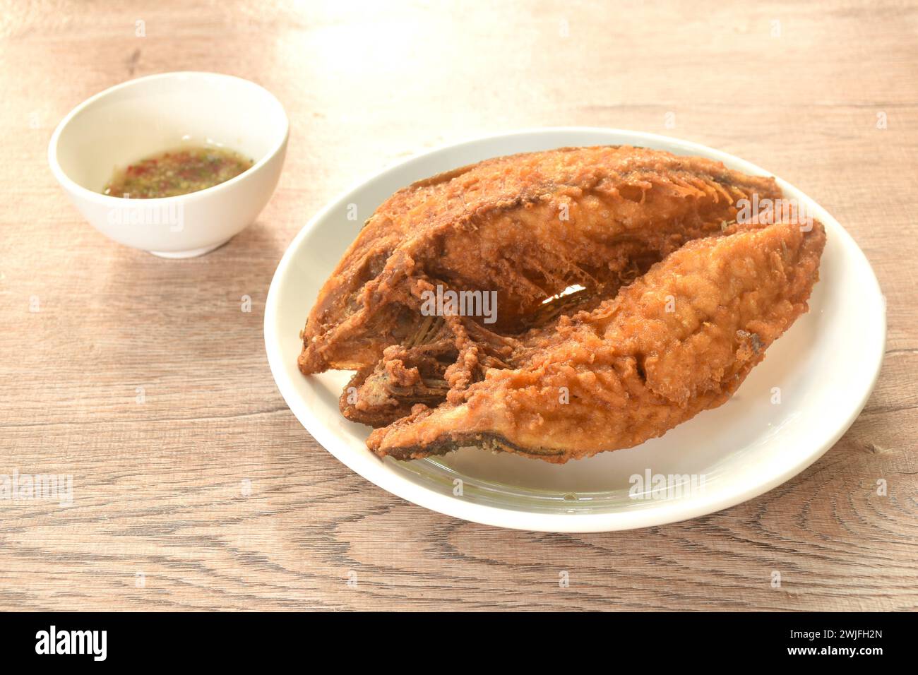 deep fried black-banded trevally fish on plate dipping spicy chili ...