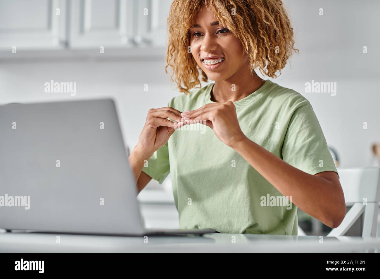 smiling african american woman in braces using sign language during ...