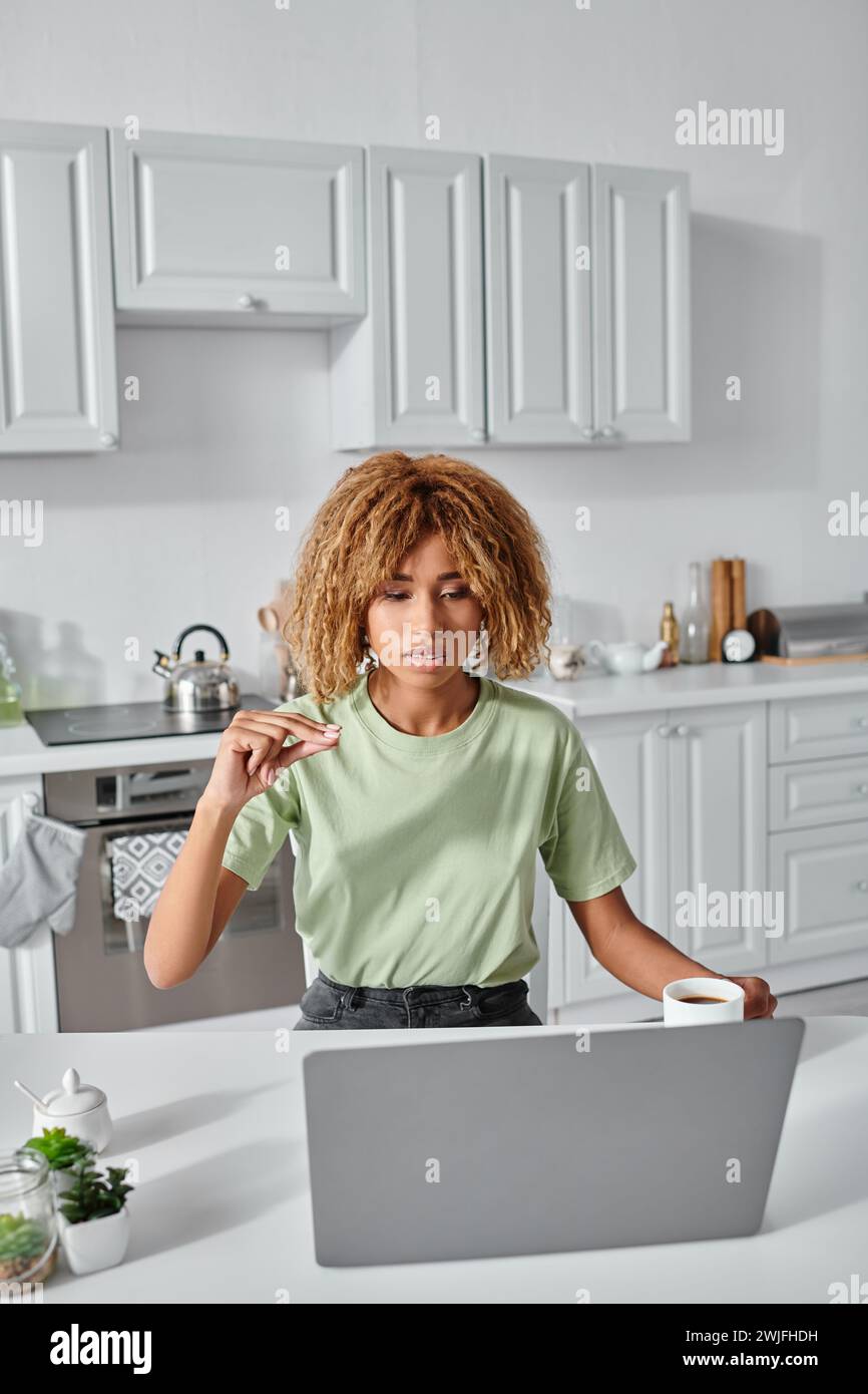 focused african american woman using sign language during video call ...