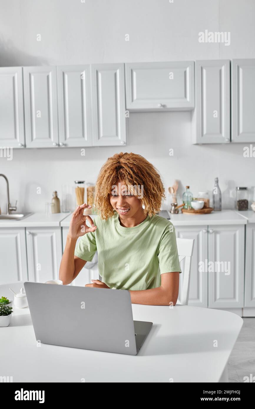 smiling african american woman using sign language during a video call ...