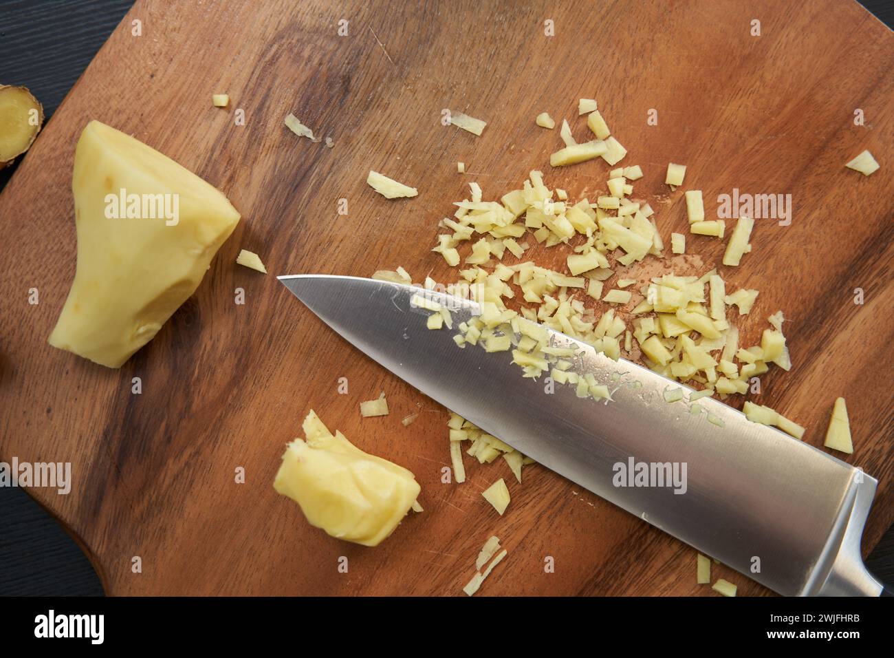 Man chef chopping ginger finely on a wooden board with a very sharp ...
