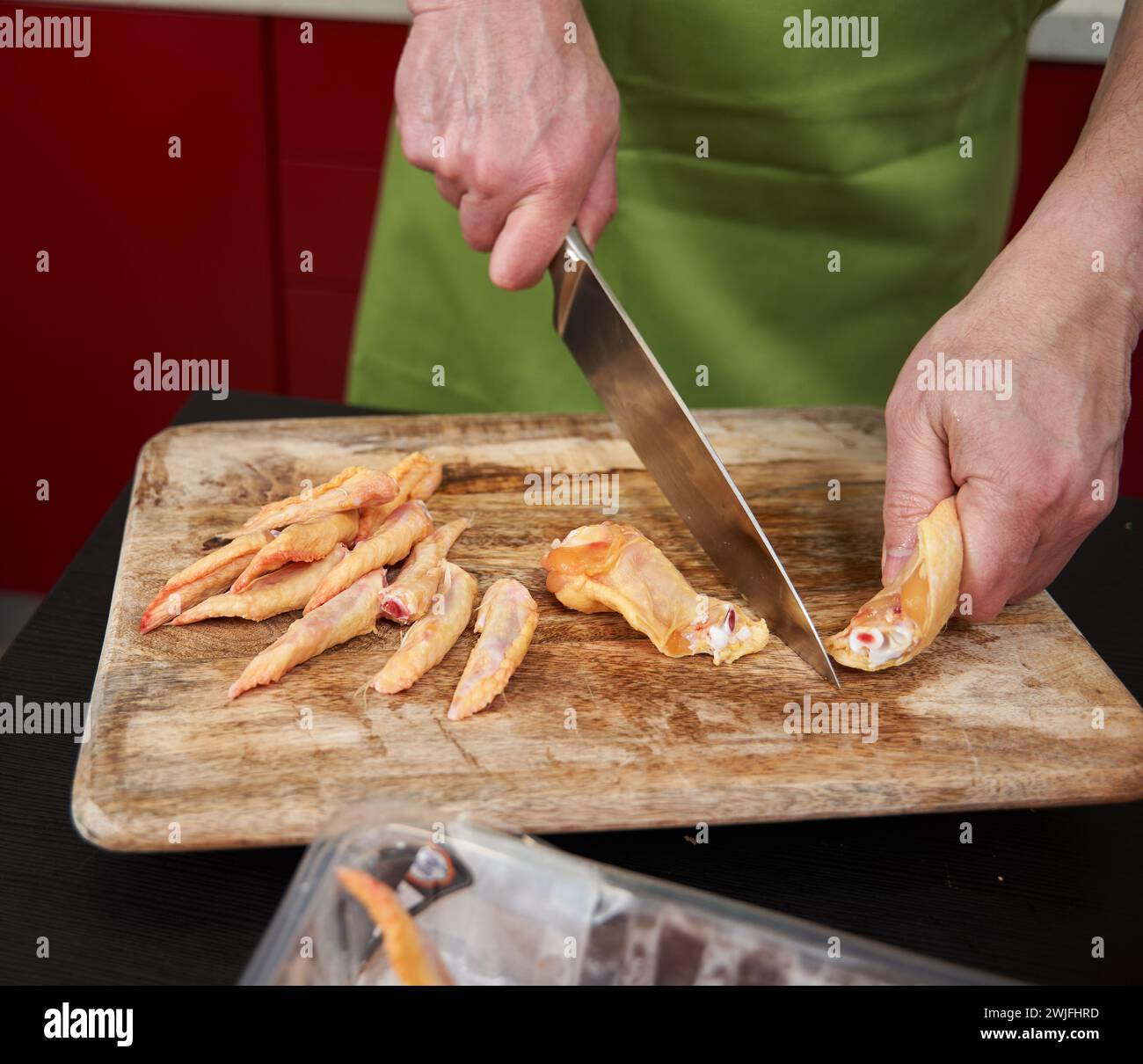 Man cook removing tips from chicken wings and cutting them in half for ...