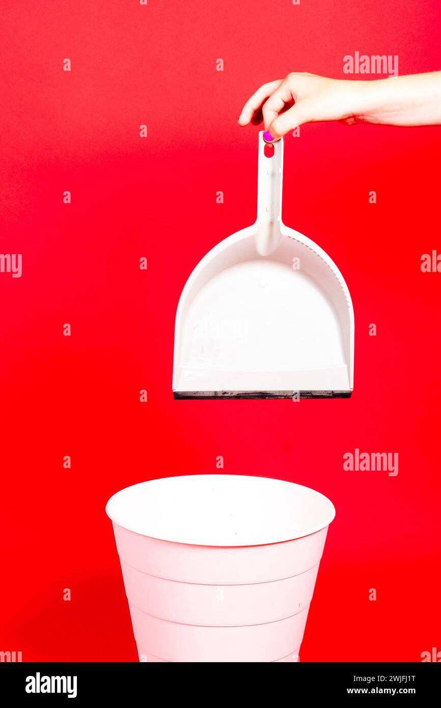 Woman throwing crumpled paper from scoop into rubbish bin on red ...