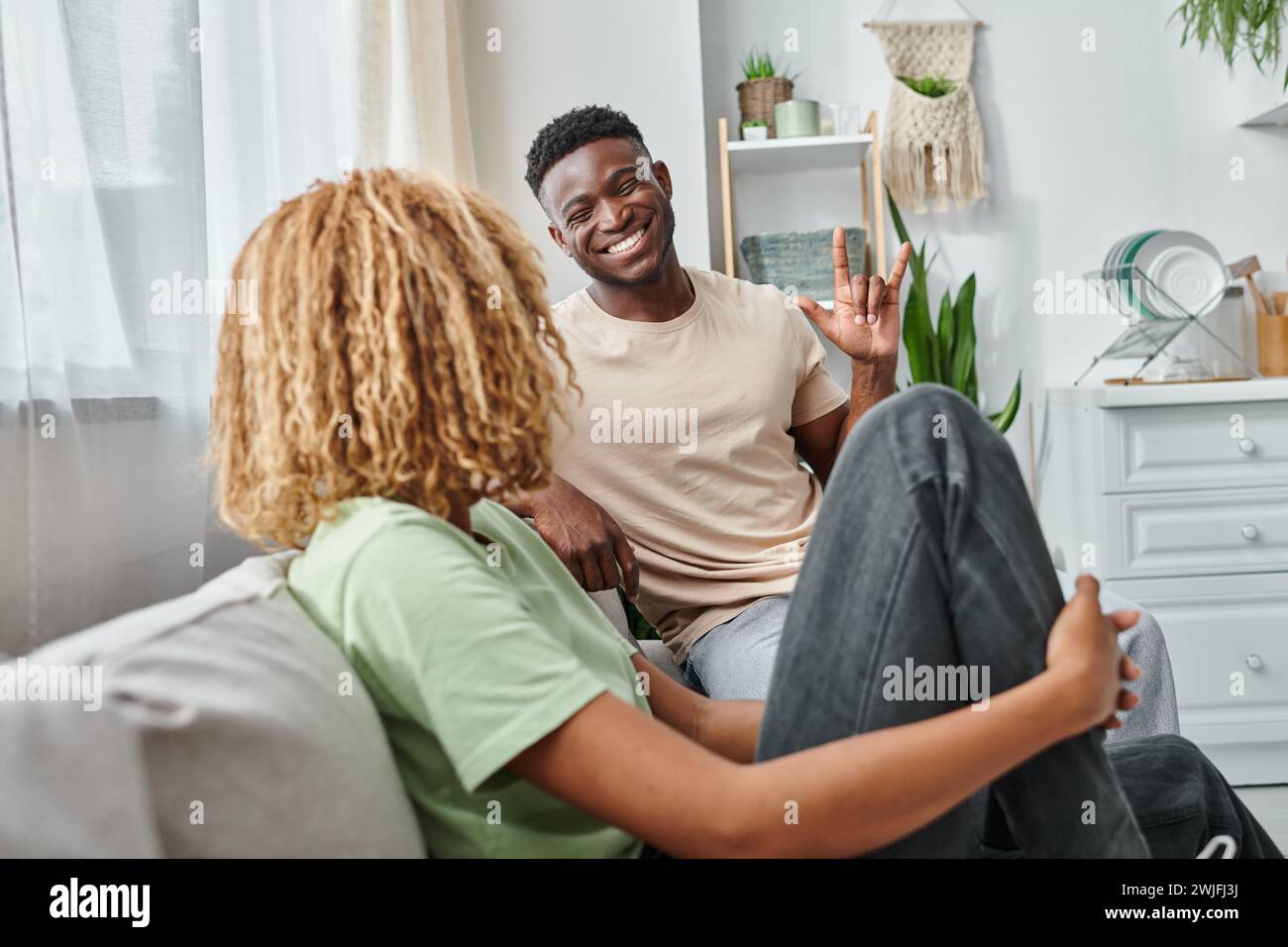 happy black man smiling while communicating with sign language with ...