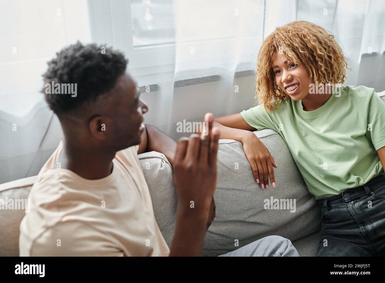 sign language, joyful african american woman in braces looking at ...