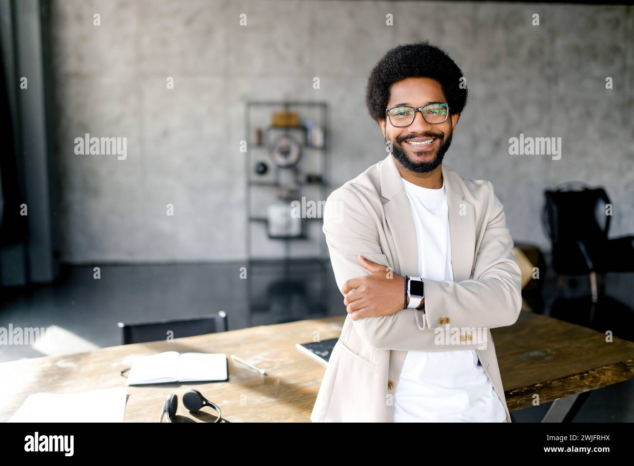 A cheerful Brazilian businessman in a smart casual beige suit stands ...