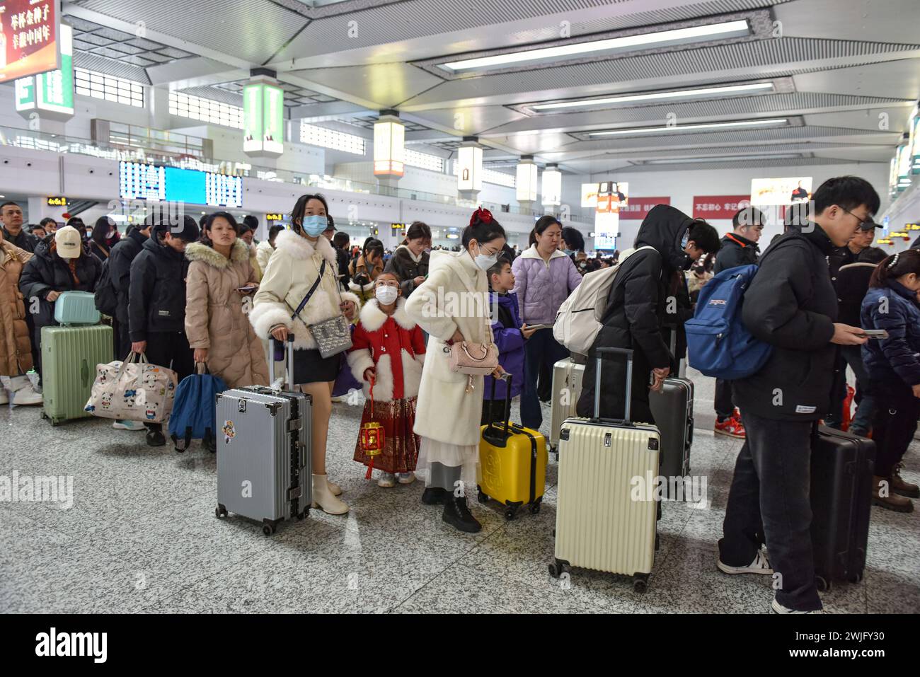 At the high-speed train station, passengers are seen carrying suitcases ...