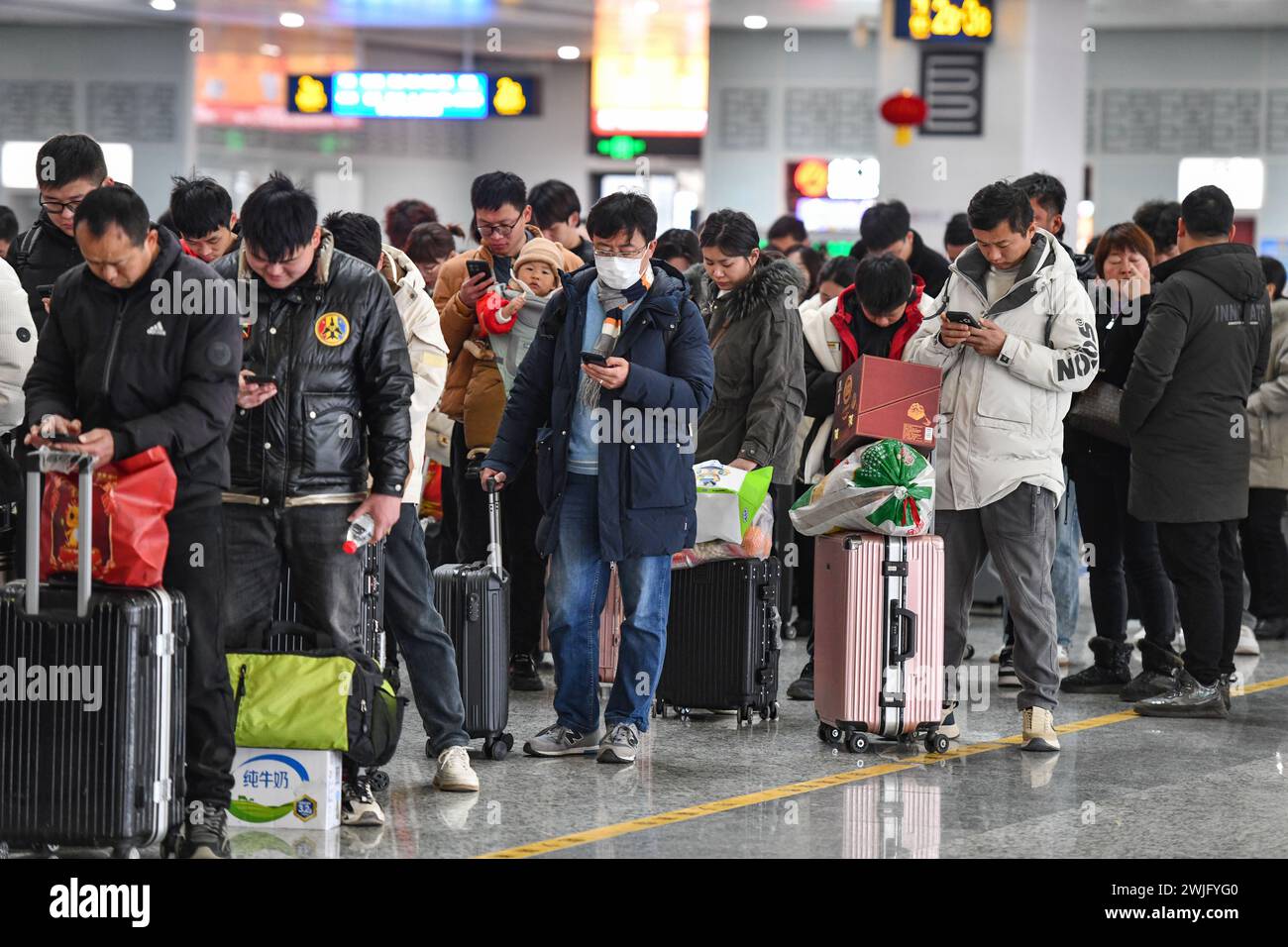 At the high-speed train station, passengers are seen carrying suitcases ...