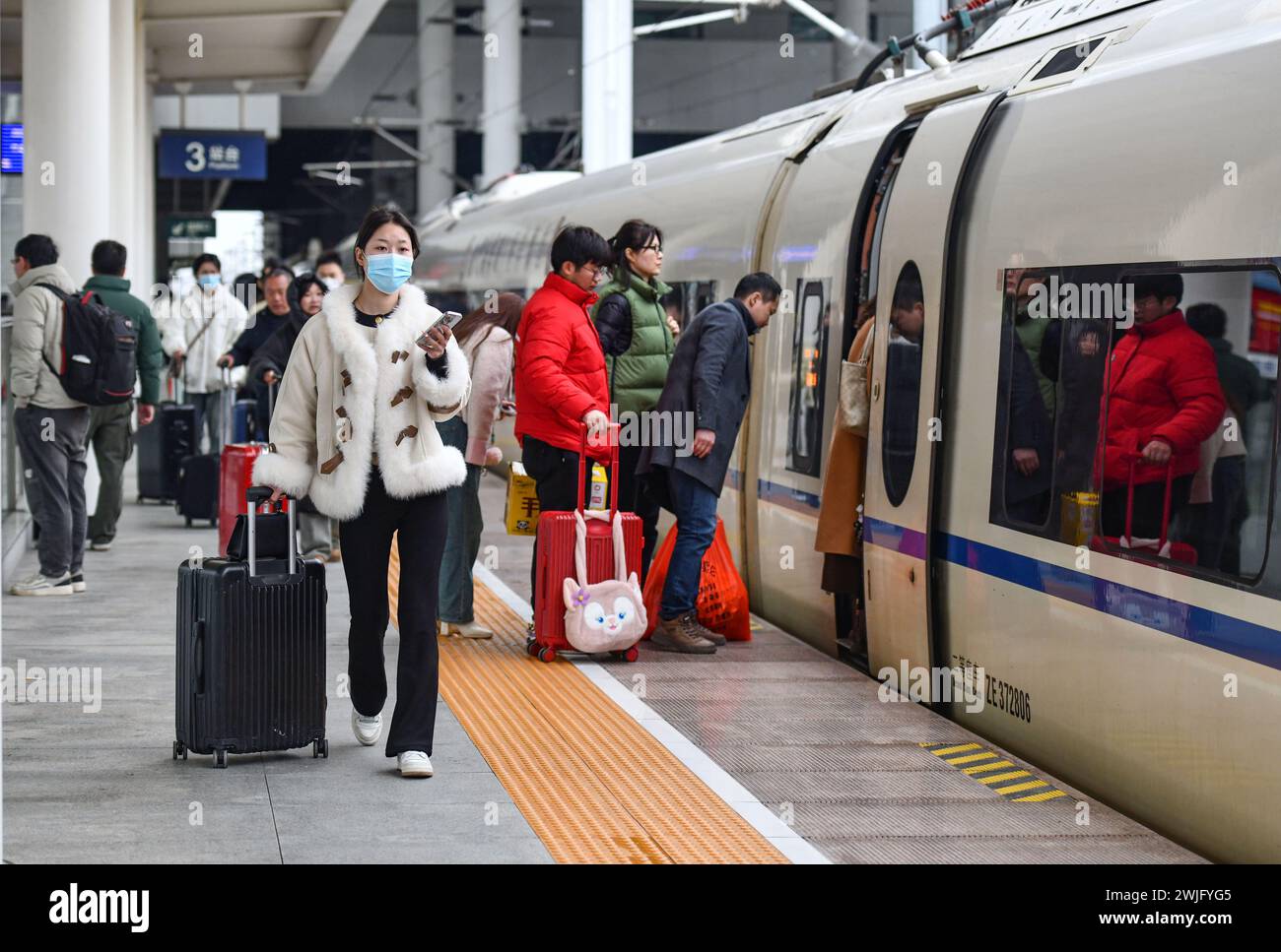 At the high-speed train station, passengers are seen carrying suitcases ...