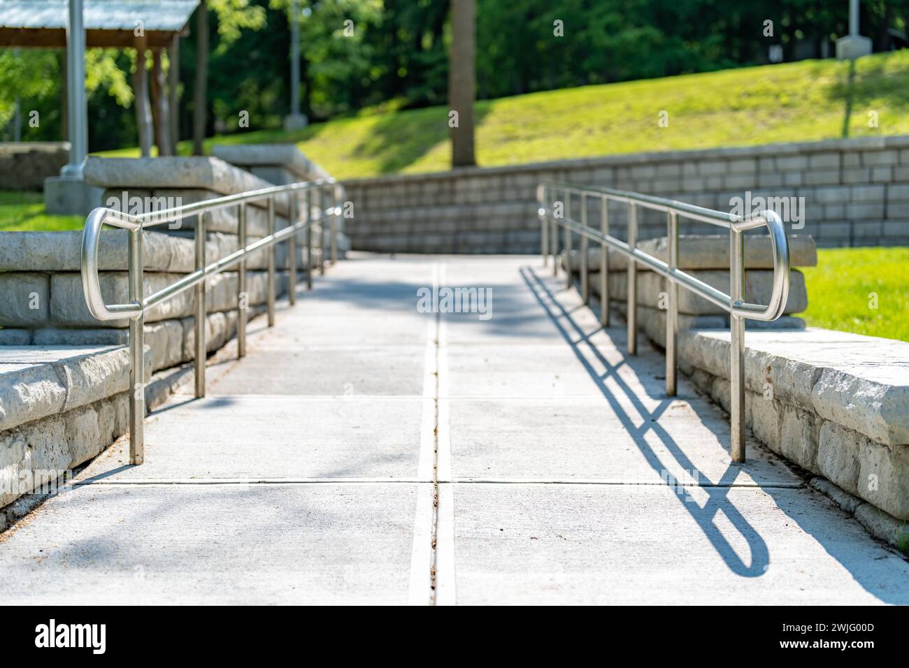 Outdoor, exterior gray concrete ramped sidewalk with stainless steel ...