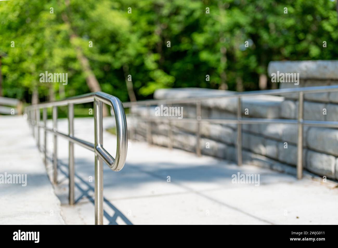 Outdoor, exterior gray concrete ramped sidewalk with stainless steel ...