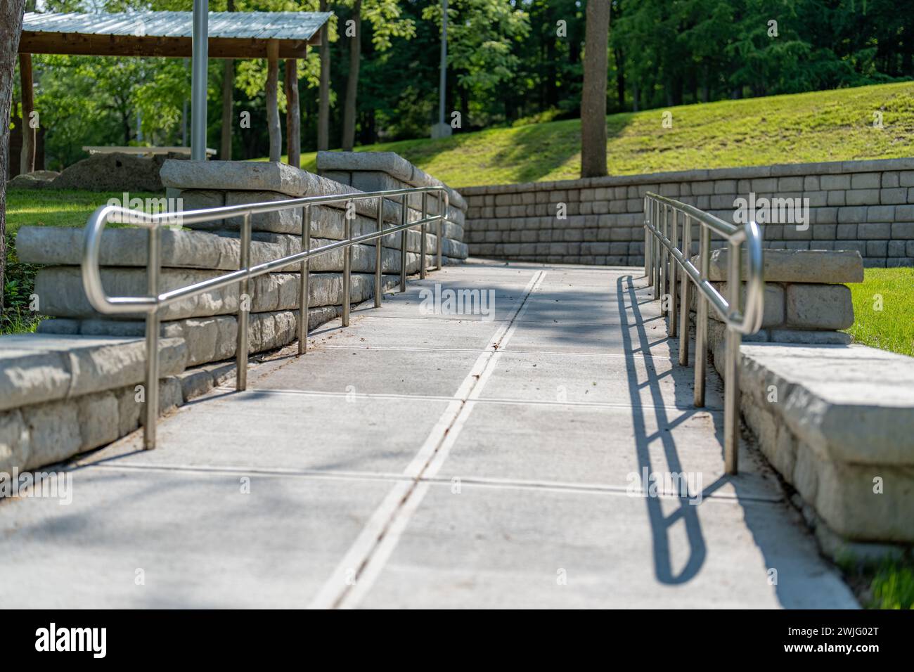 Outdoor, exterior gray concrete ramped sidewalk with stainless steel ...