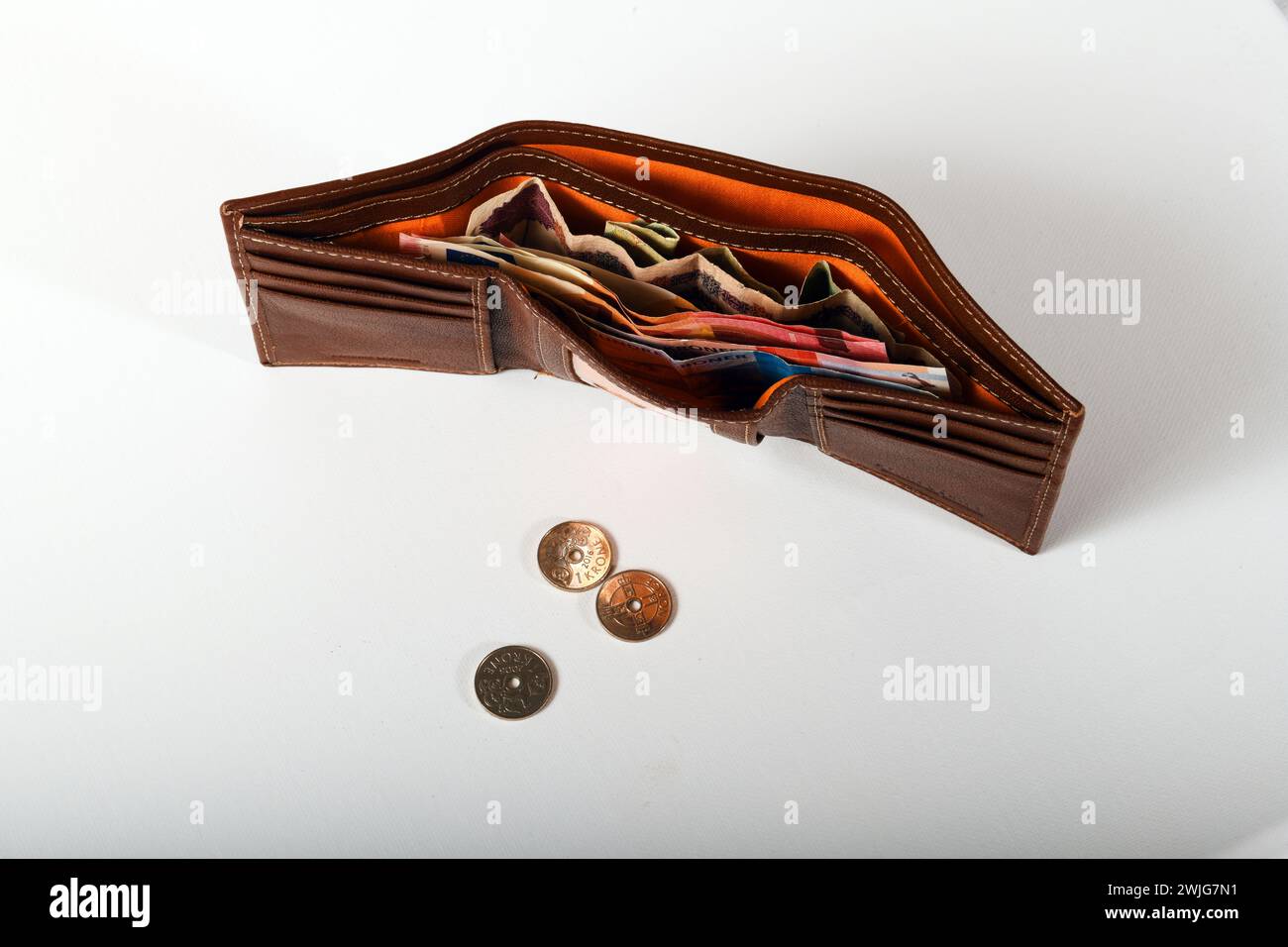 Brown wallet filled with money bills. Three Norwegian coins on the ...