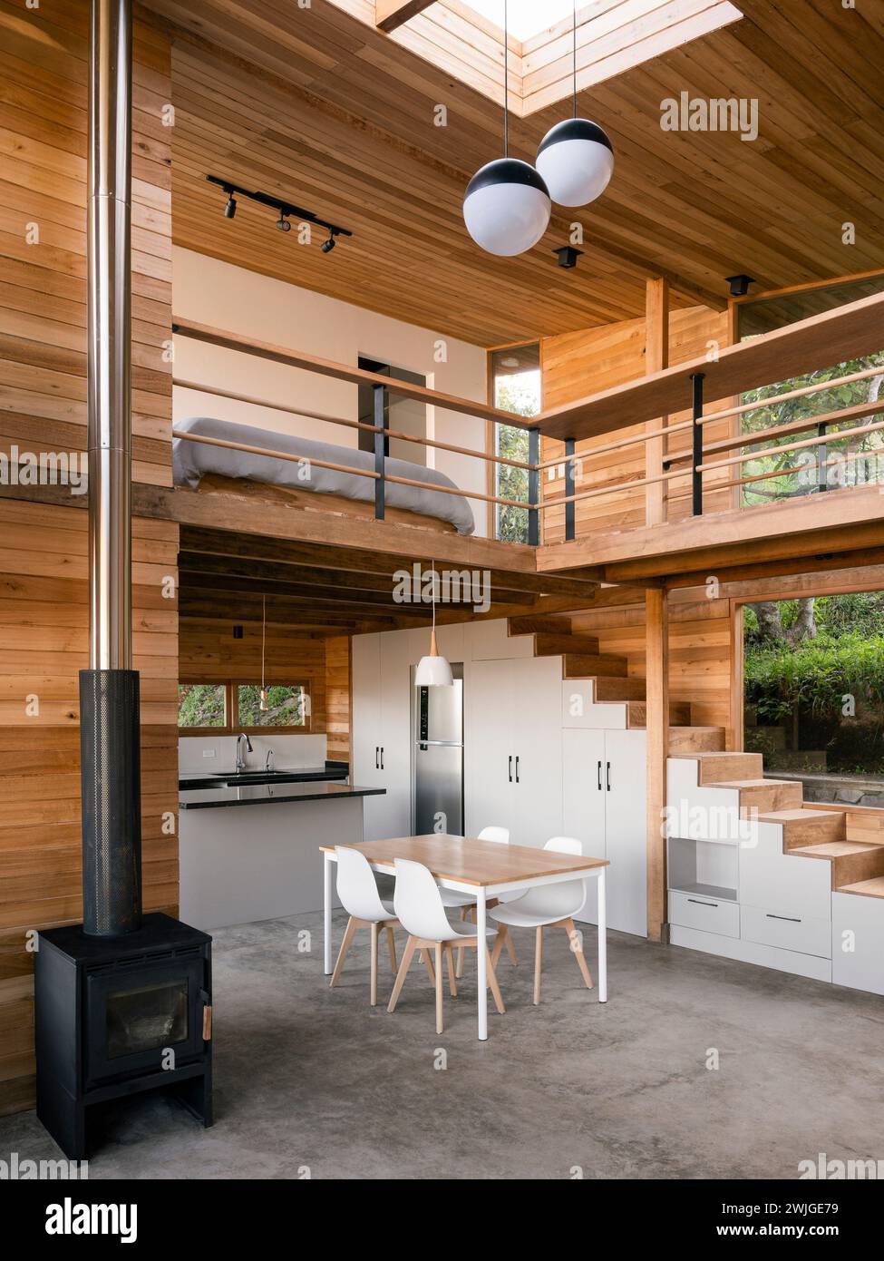 Double-height interior with living quarters, stairway and skylight ...