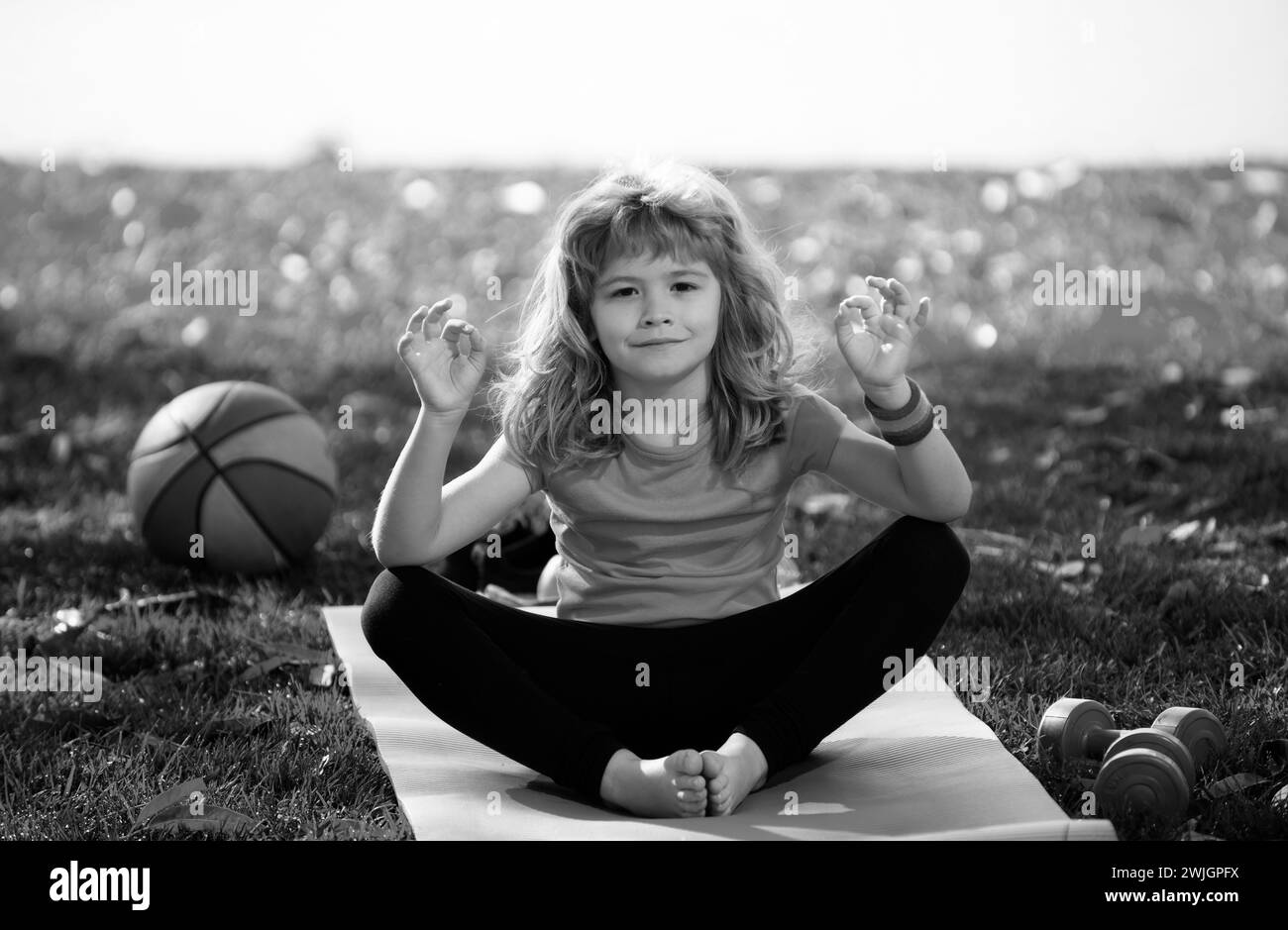 Little child sitting on the roll mat practicing meditate yoga in the ...