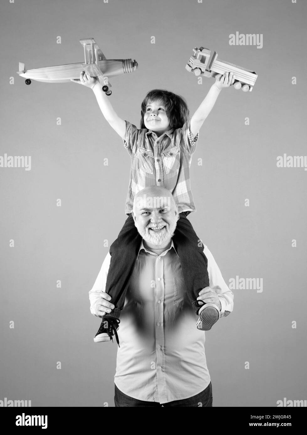 Young grandson and old grandfather piggyback playing with plane and ...