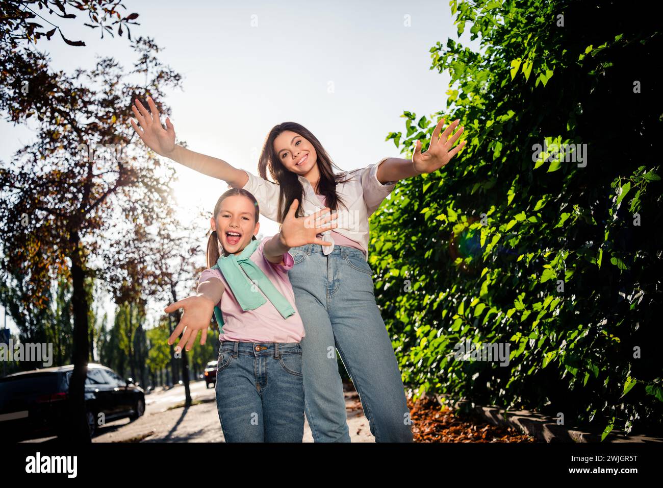 Portrait of two charming funky girls raise opened arms waving hi ...