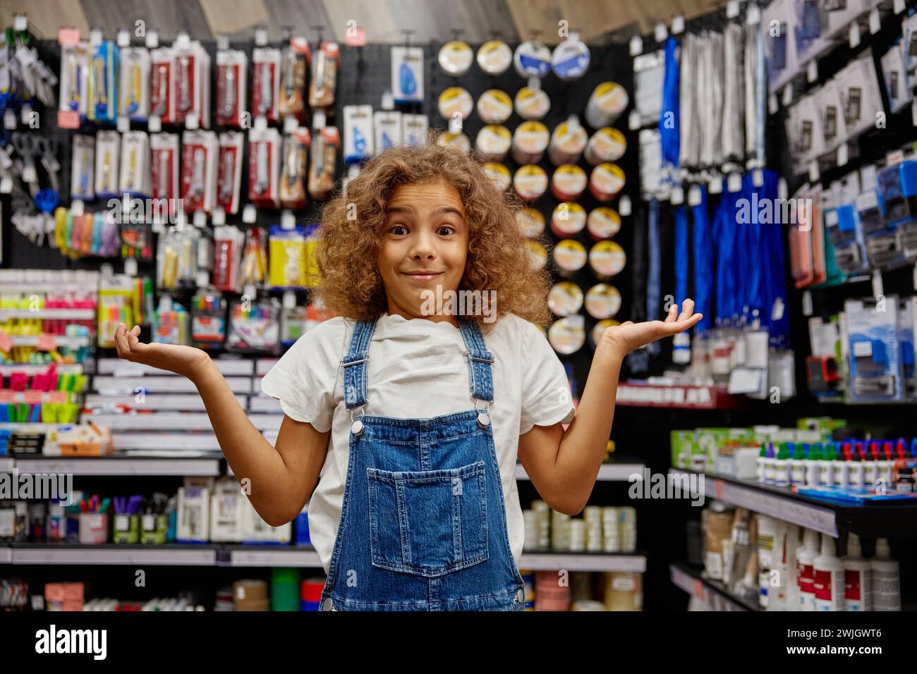 Portrait of funny school girl feeling confused standing at stationery ...