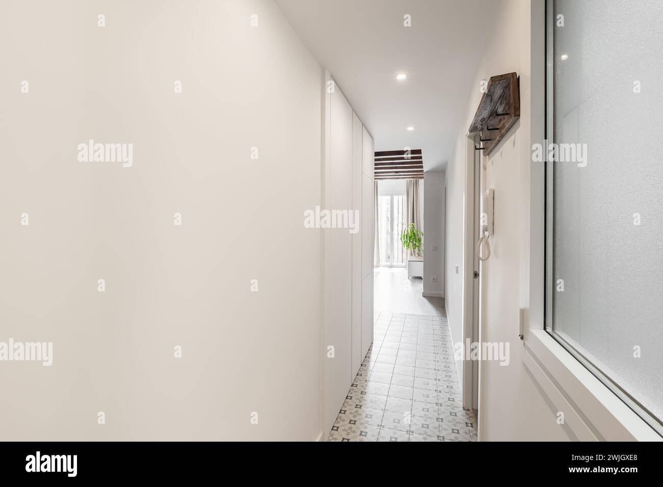 Horizontal shot of a long bright corridor with an entrance door and a ...