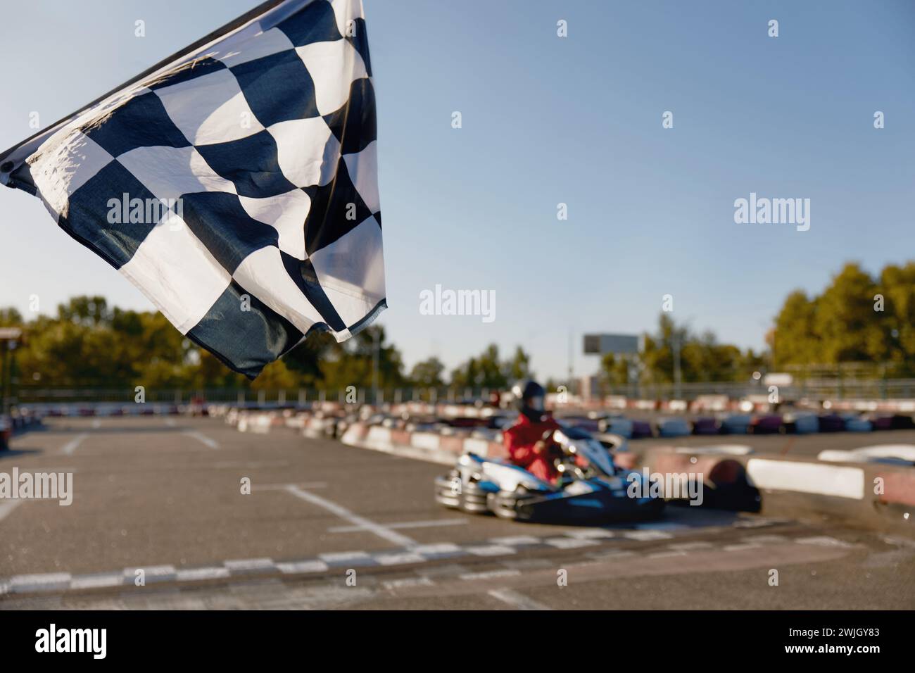 Go-kart driver crossing at finish line moving to checkered racing flag ...