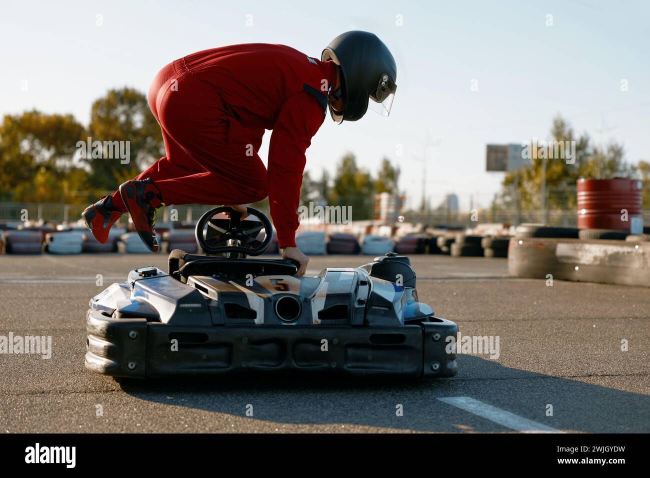 Excited man driver jumping into go-cart getting ready for speed race ...