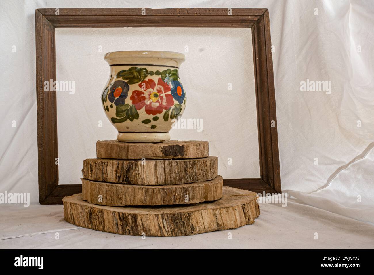 Hand made ceramic vessel on tree trunk rings with wooden frame on dirty ...