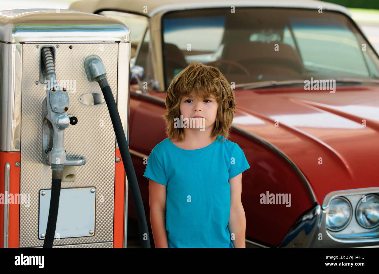 Kid boy at the gas station. Waiting for fuel. Kid fueling retro car at ...