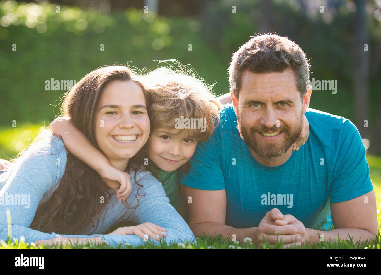 Cute family portrait hugging and embracing. Family lying on grass in ...
