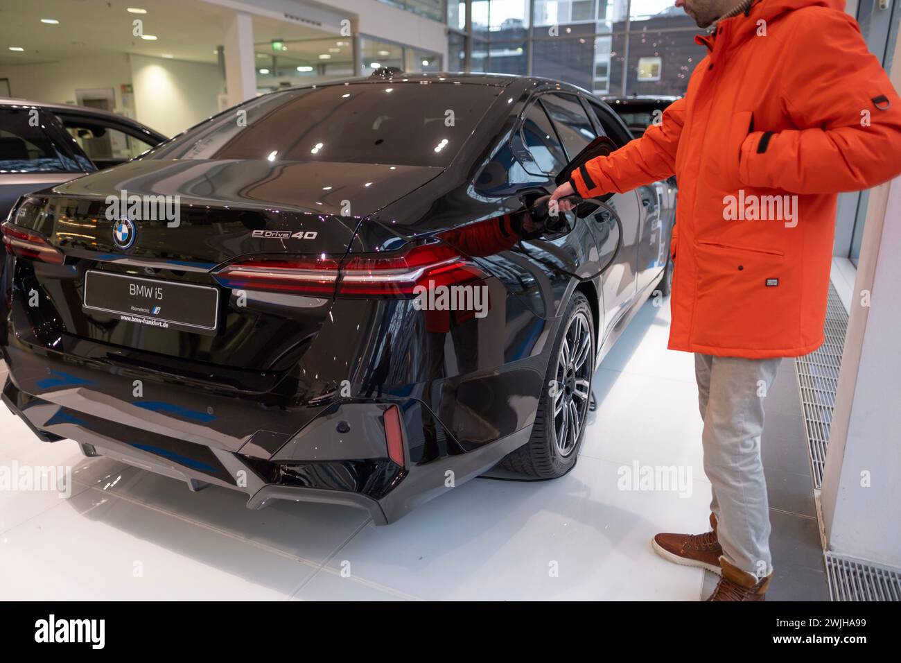 young man examines, chooses new black BMW i5 eDrive40 all-electric ...