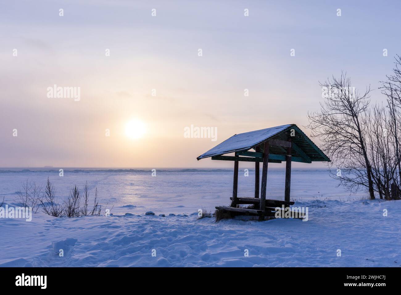 Winter landscape with an empty wooden gazebo on snow covered beach ...
