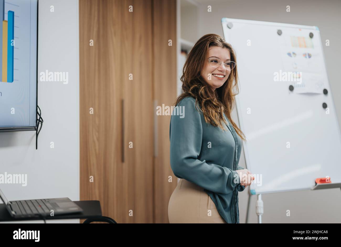 Engaging young woman giving a presentation in a well-lit office, with a ...