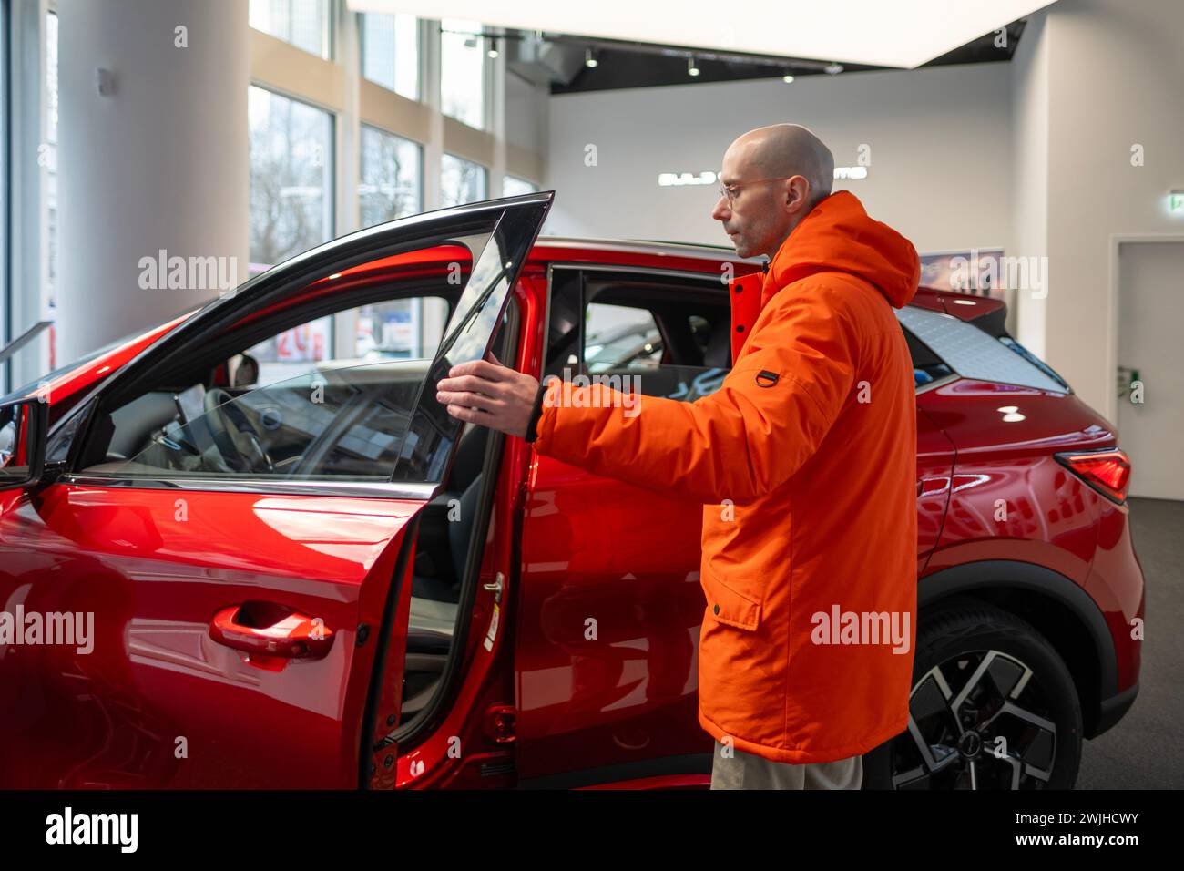 young man examines, chooses new red BYD ATTO 3 Car in Studio, test ...