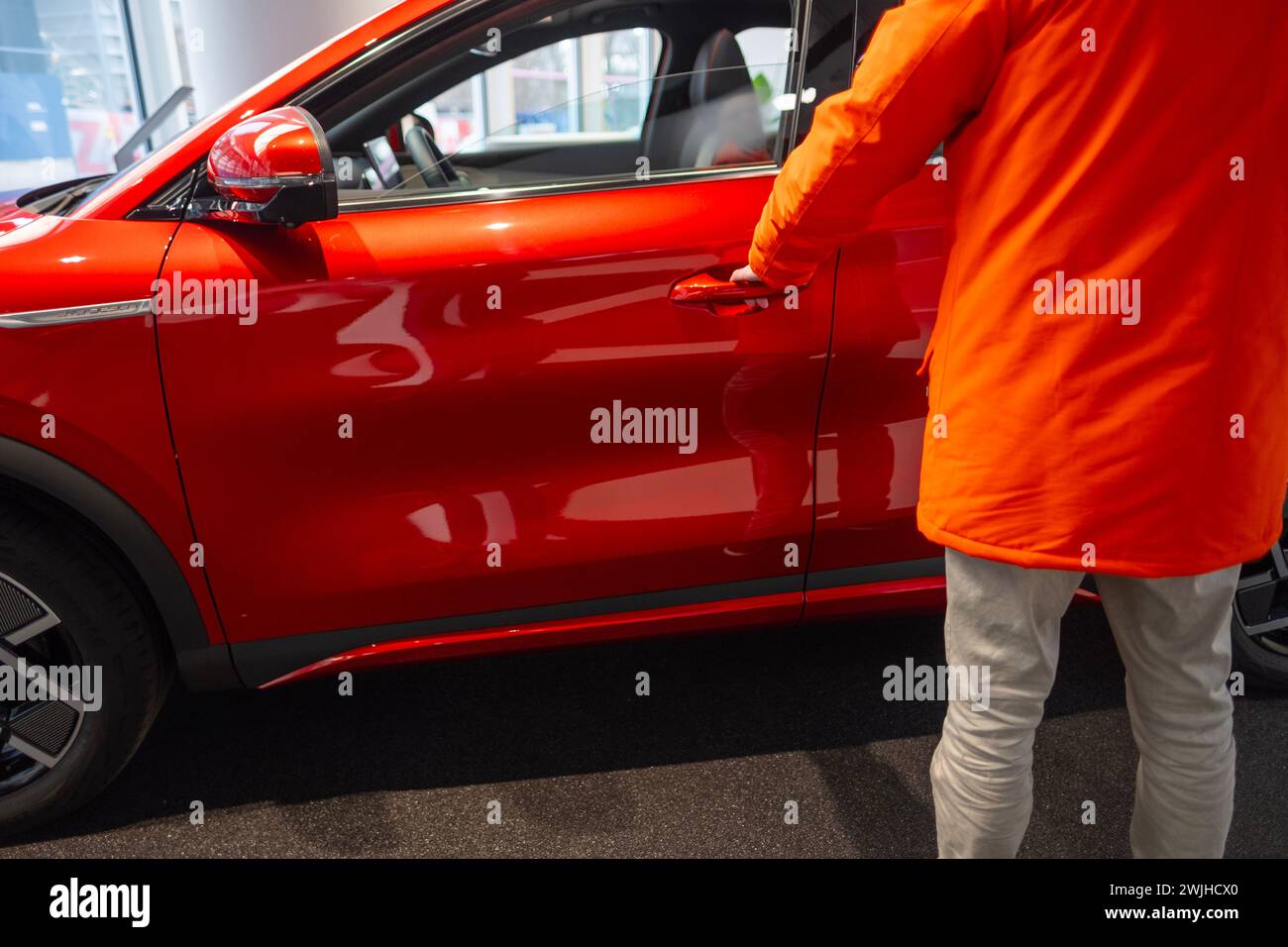 young man examines, chooses new red BYD ATTO 3 Car in Studio, test ...