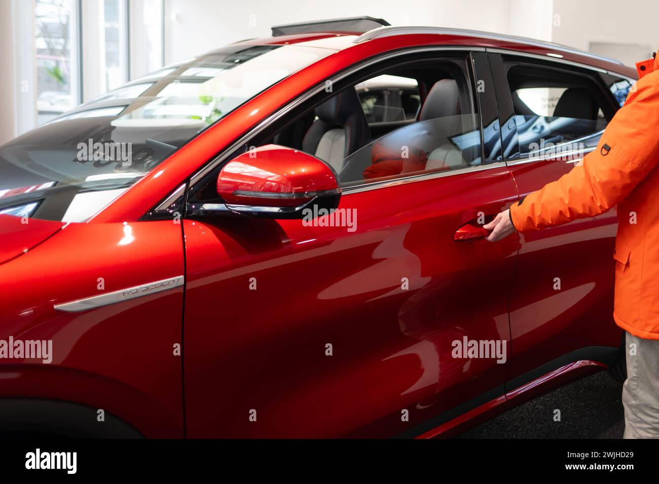 young man examines, chooses new red BYD ATTO 3 Car in Studio, test ...