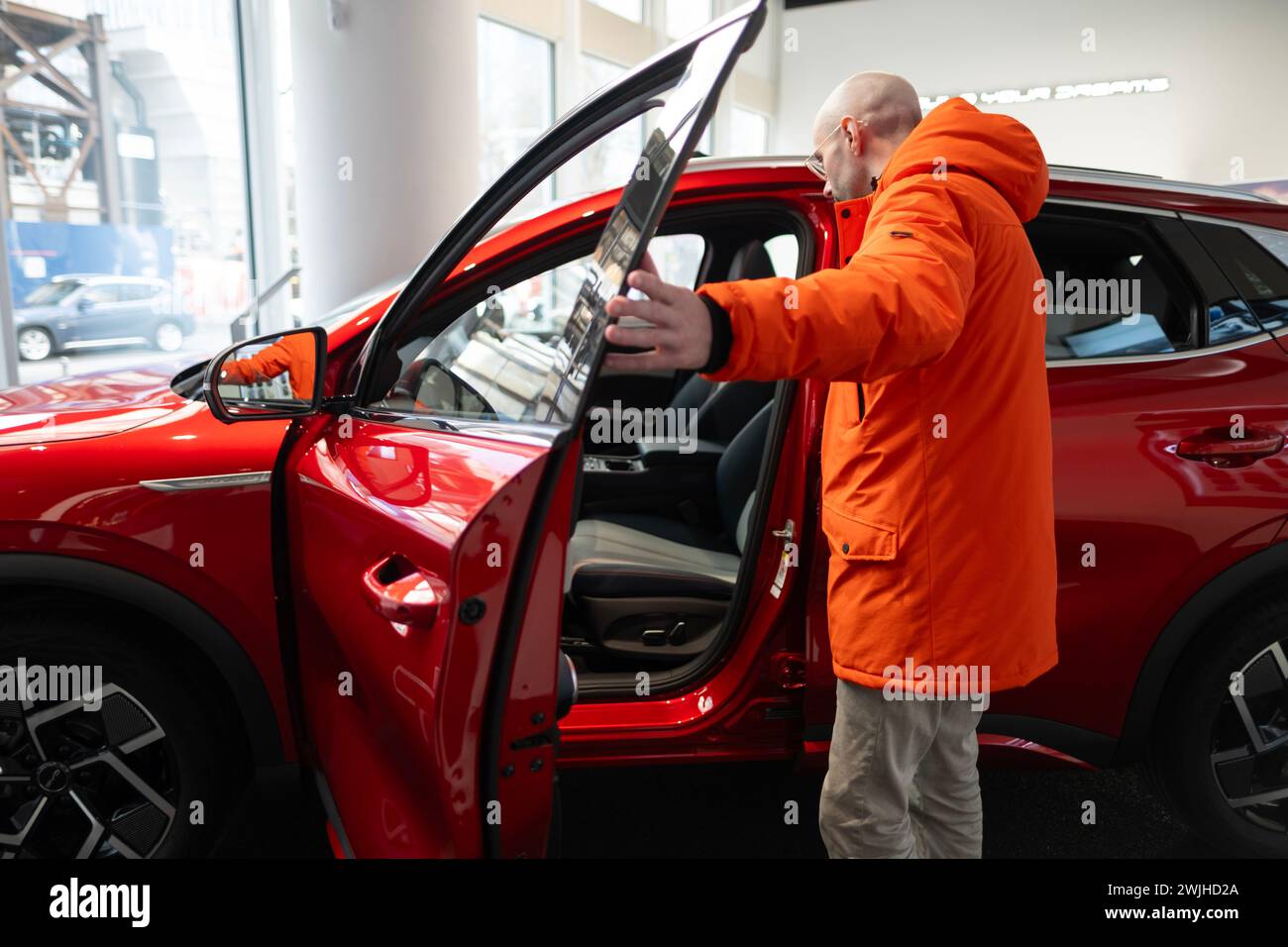 young man examines, chooses new red BYD ATTO 3 Car in Studio, test ...