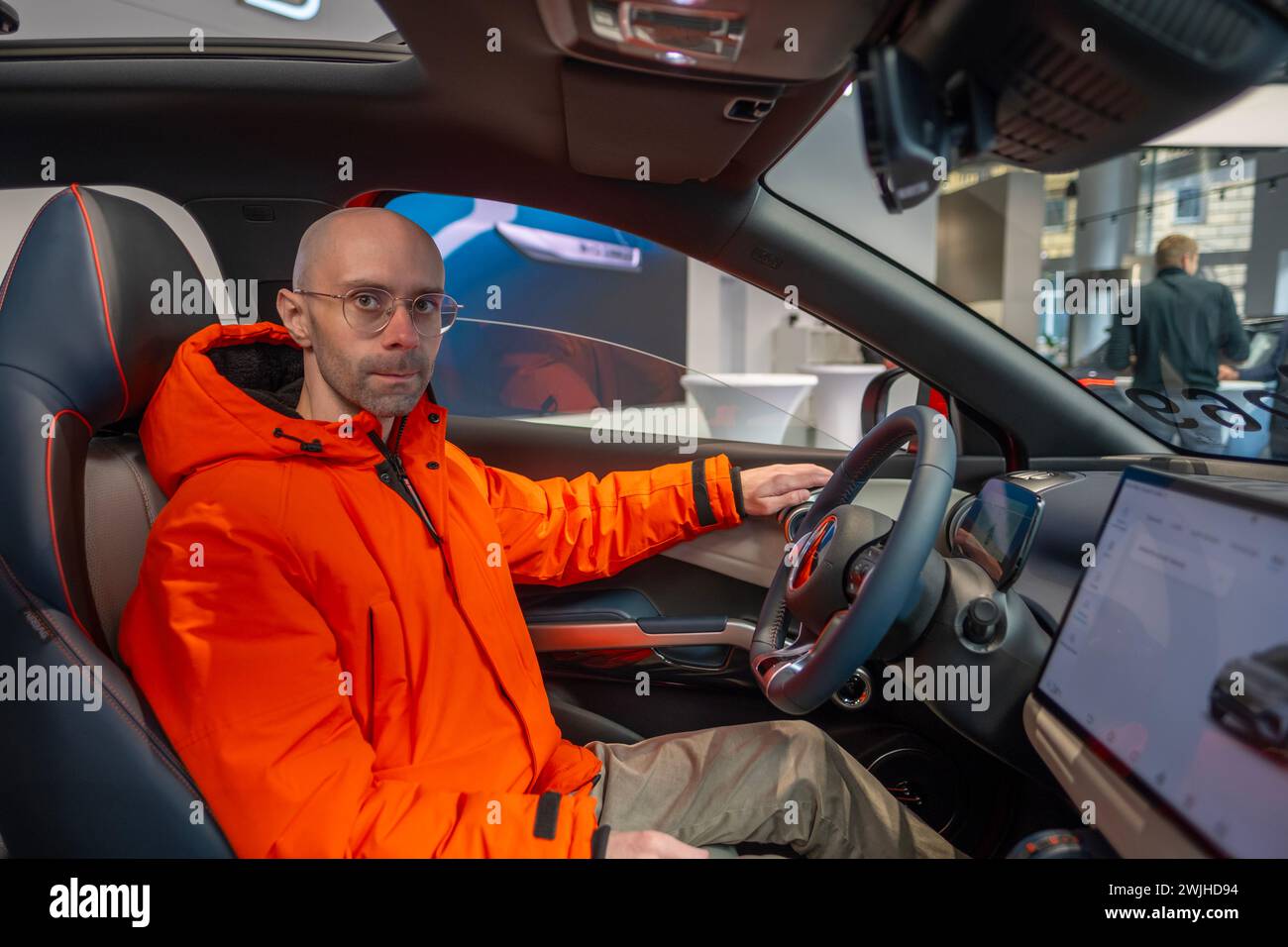young man examines, chooses new red BYD ATTO 3 Car, behind steering ...