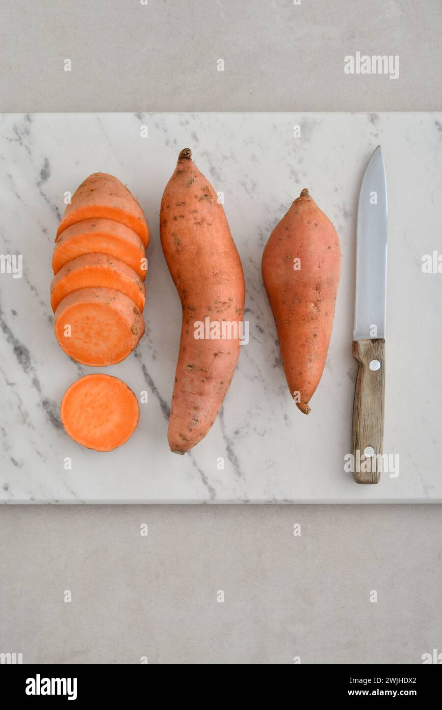 Set of fresh whole and sliced sweet potatoes on light background. Top ...